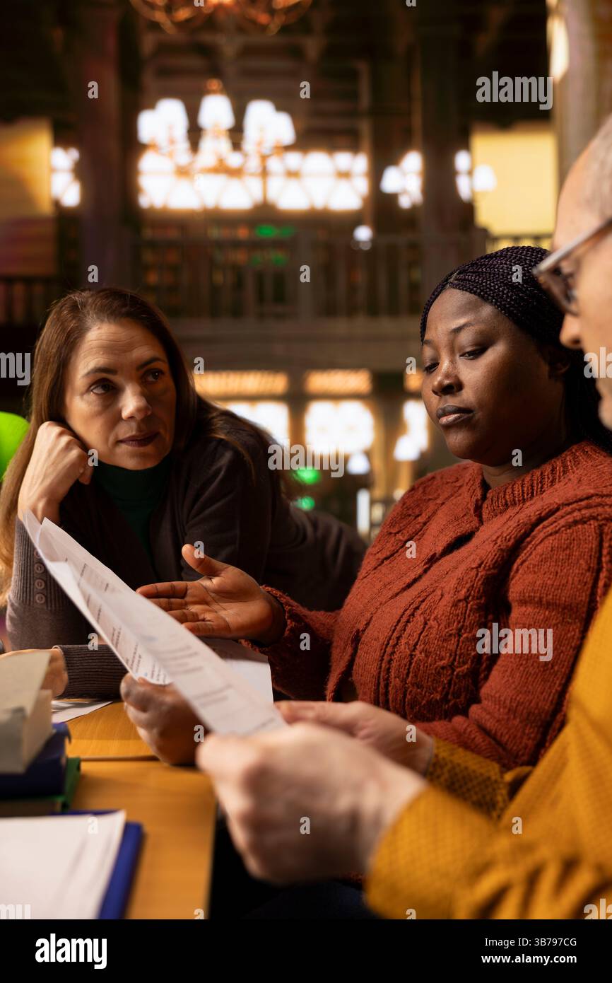 Multiethnic group of mature scholars working on their thesis paperwork ...