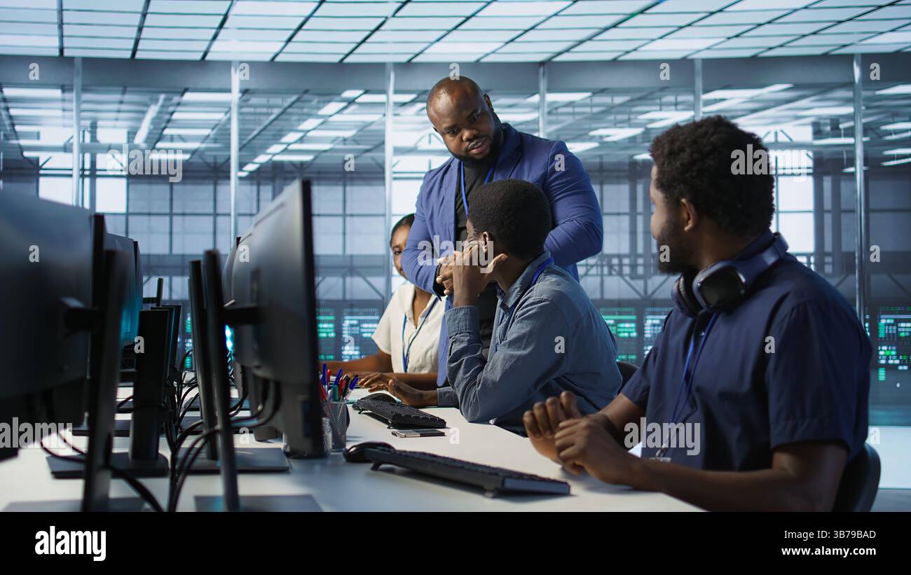 Data center team leader supervising engineers implementing AI predictive maintenance systems ...