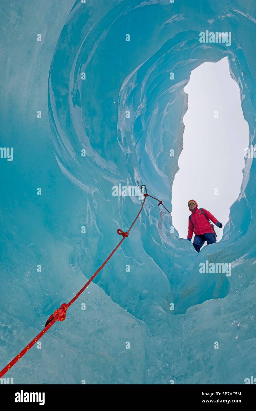 Ice climber looking down ice cave, Fox Glacier, South Island, New ...