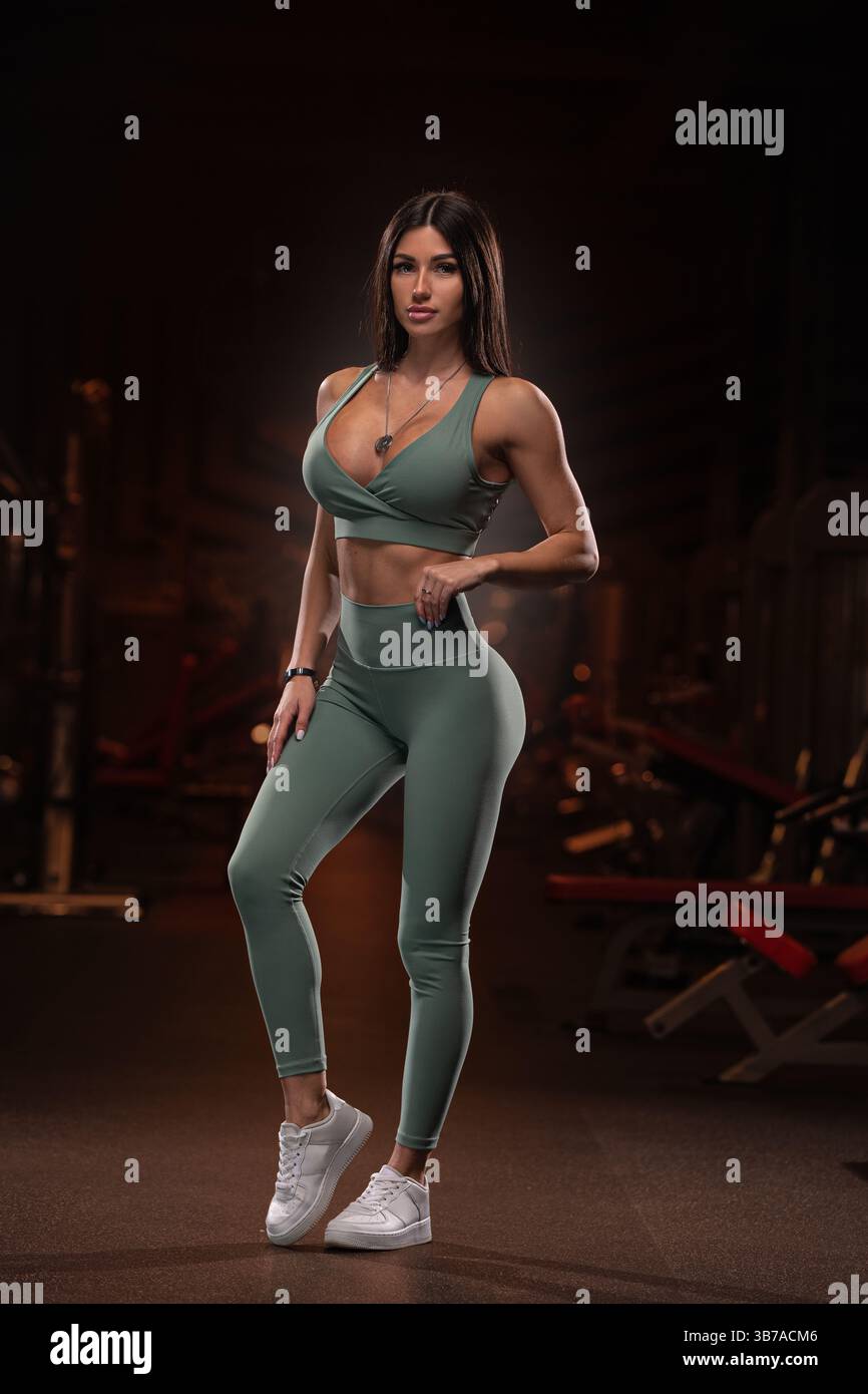 gym setting fitness model stands poise while wearing form fitting athletic wear. confident pose ...