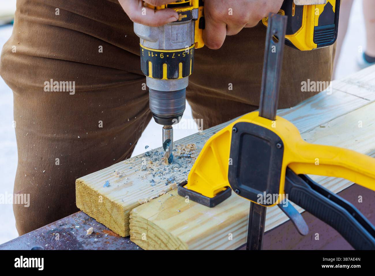 Metalworker uses drill to create holes in wooden planks while working ...