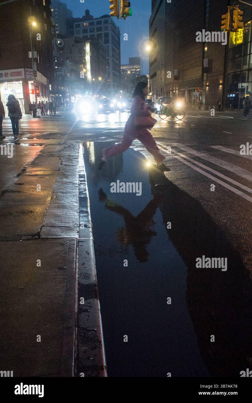 May 5, 2025, New York City, New York, USA: Jumping over a large puddle ...