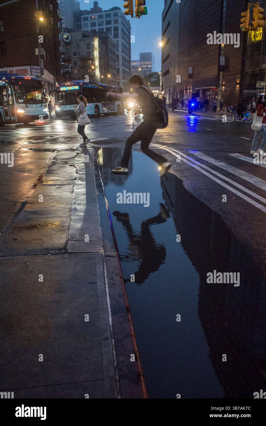 May 5, 2025, New York City, New York, USA: Jumping over a large puddle ...