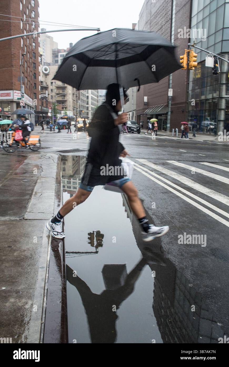 May 5, 2025, New York City, New York, USA: Jumping over a large puddle ...