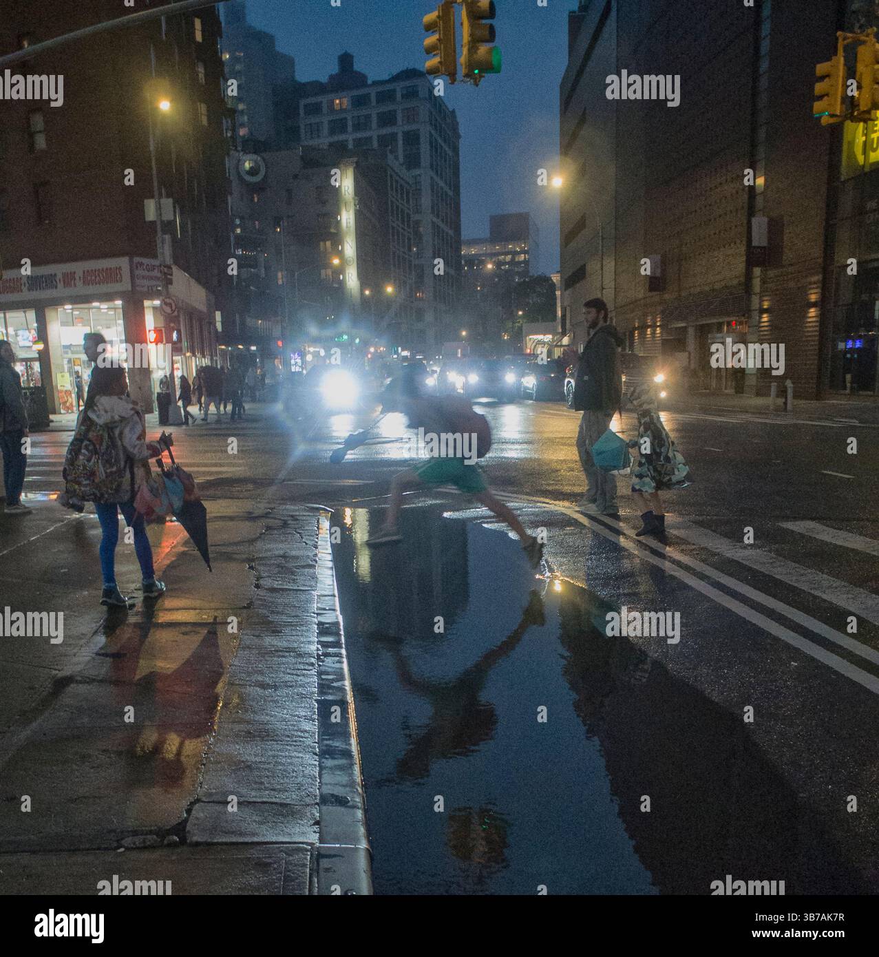 May 5, 2025, New York City, New York, USA: Jumping over a large puddle ...