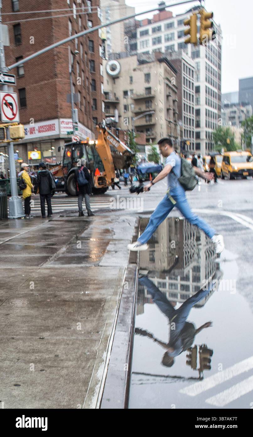 May 5, 2025, New York City, New York, USA: Jumping over a large puddle ...
