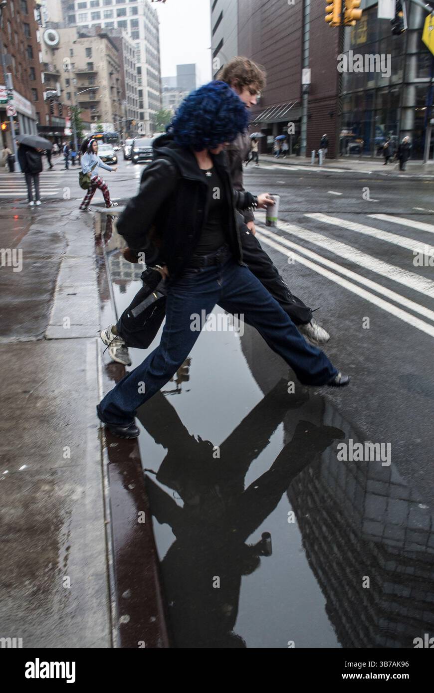May 5, 2025, New York City, New York, USA: Jumping over a large puddle ...