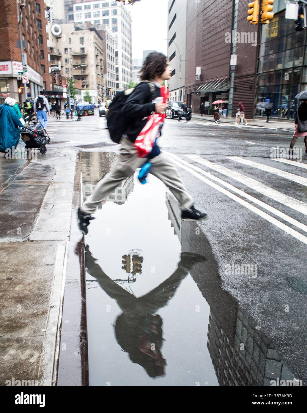 May 5, 2025, New York City, New York, USA: Jumping over a large puddle ...