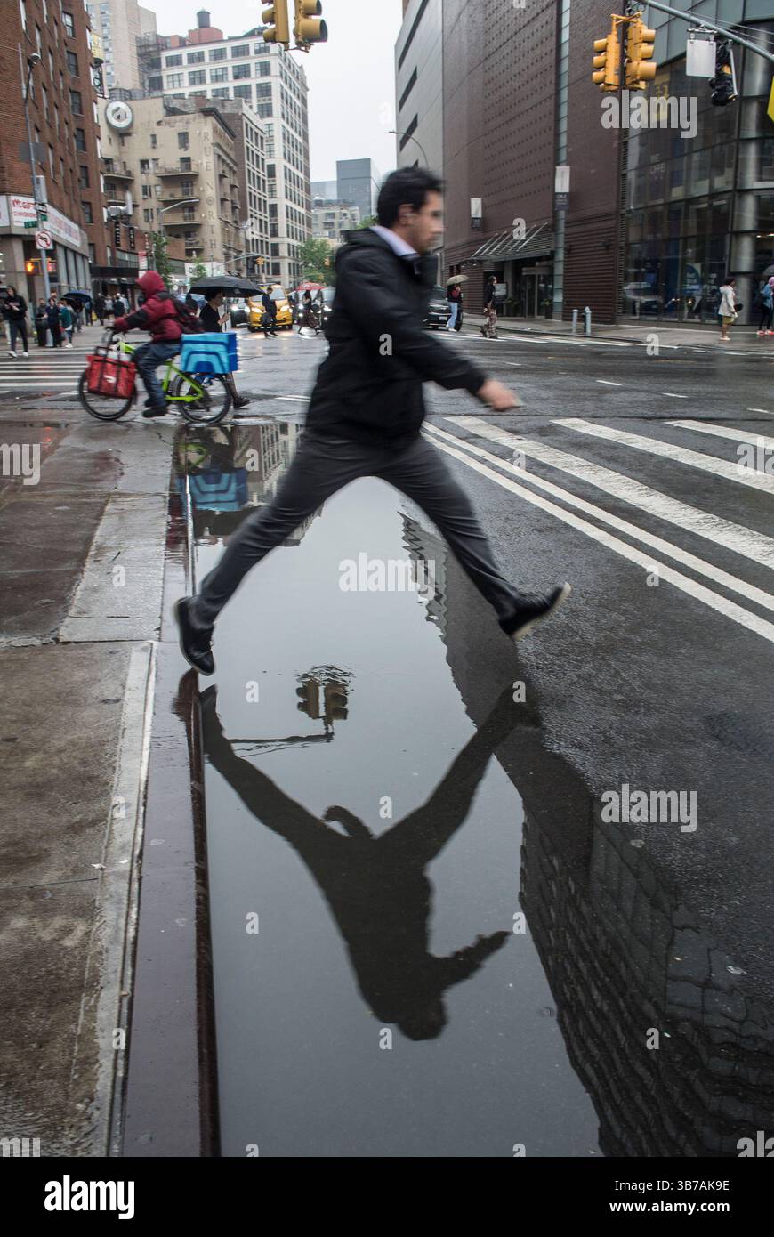 May 5, 2025, New York City, New York, USA: Jumping over a large puddle ...