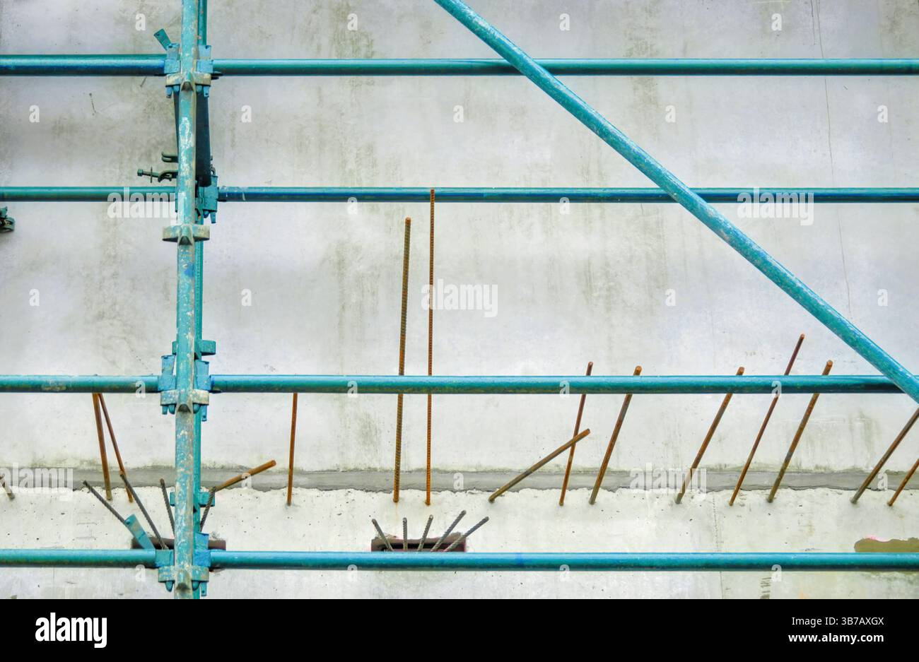 Graphic detail of blue scaffolding and exposed rebar at a building site ...