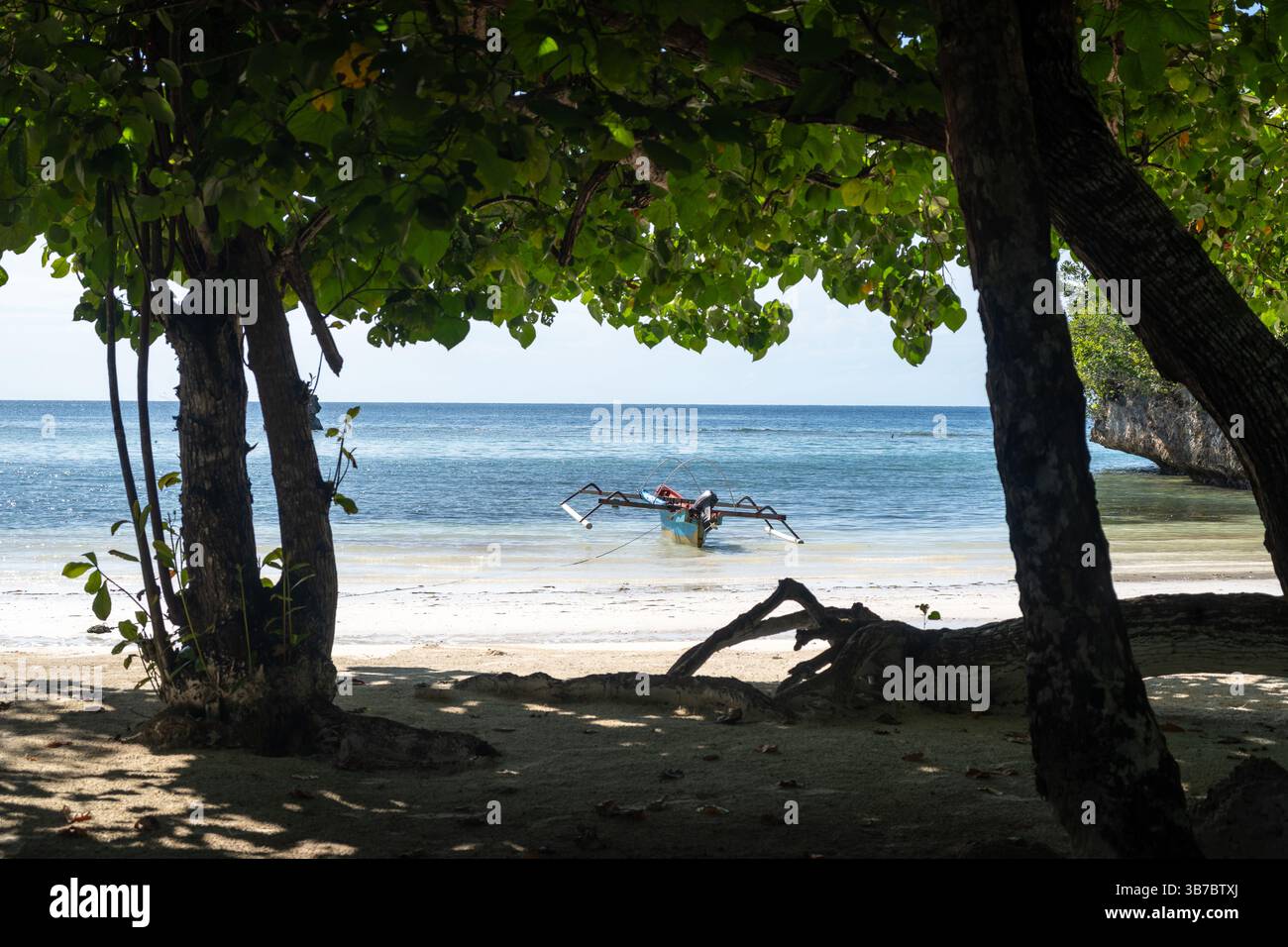 A traditional wooden boat floats near the white sands of Lia beach ...