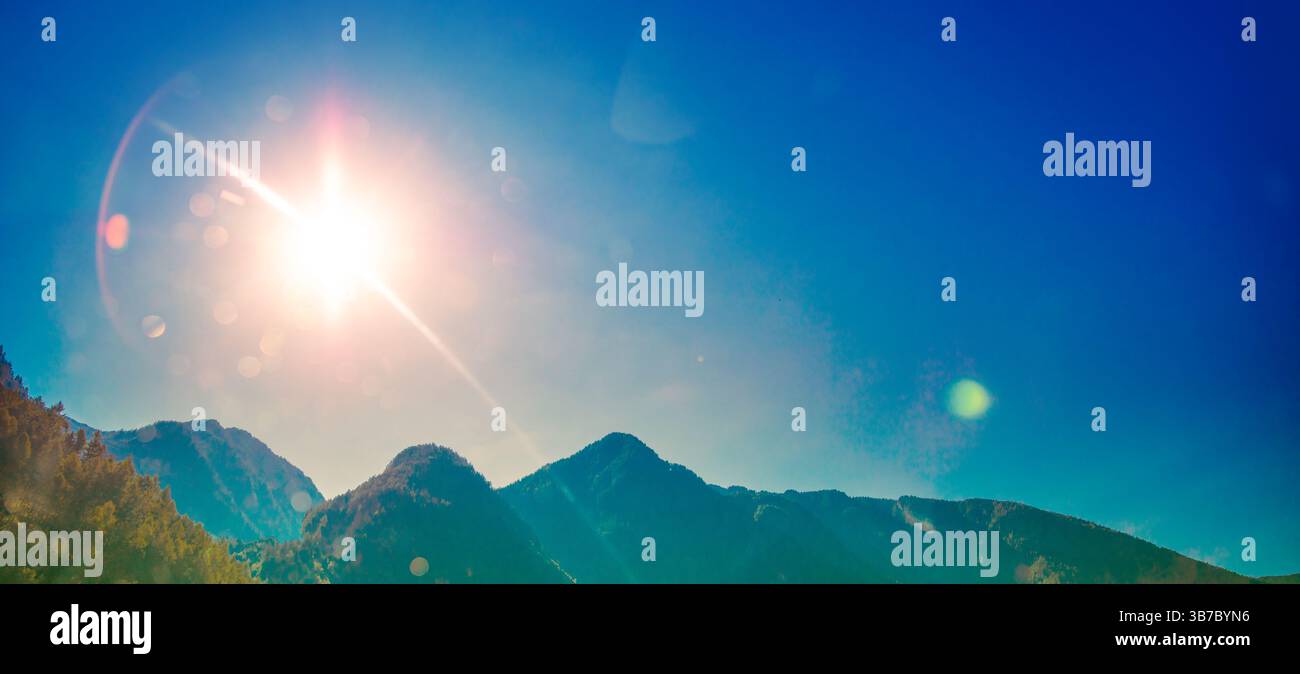 Silhouette of mountains against a clear blue sky with sun. Horizontal ...