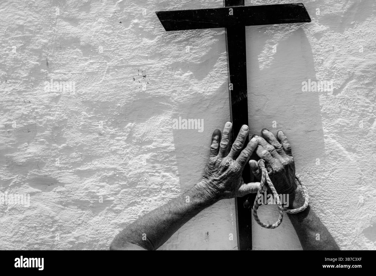 An Afro-Colombian man prays at a prayer station marked by a wooden ...