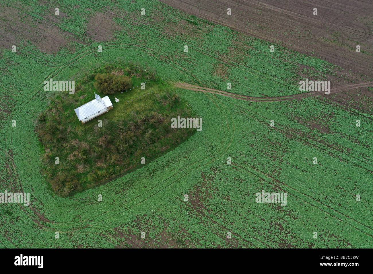 Aerial view of small white chapel in the middle of agricultural field ...