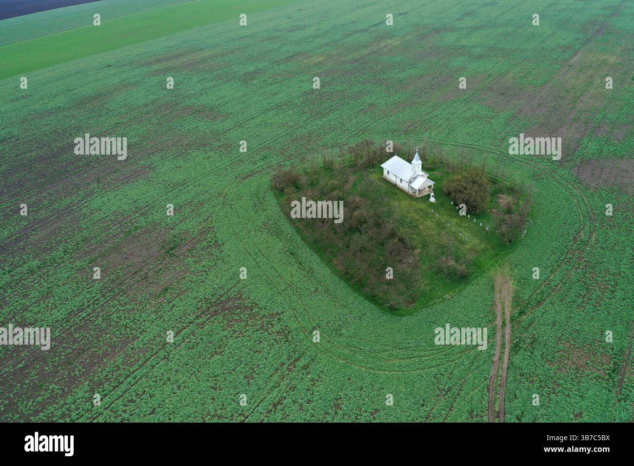 Aerial view of small white chapel in the middle of agricultural field ...
