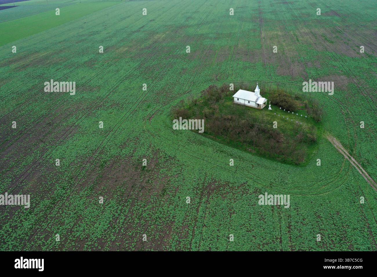 Aerial view of small white chapel in the middle of agricultural field ...