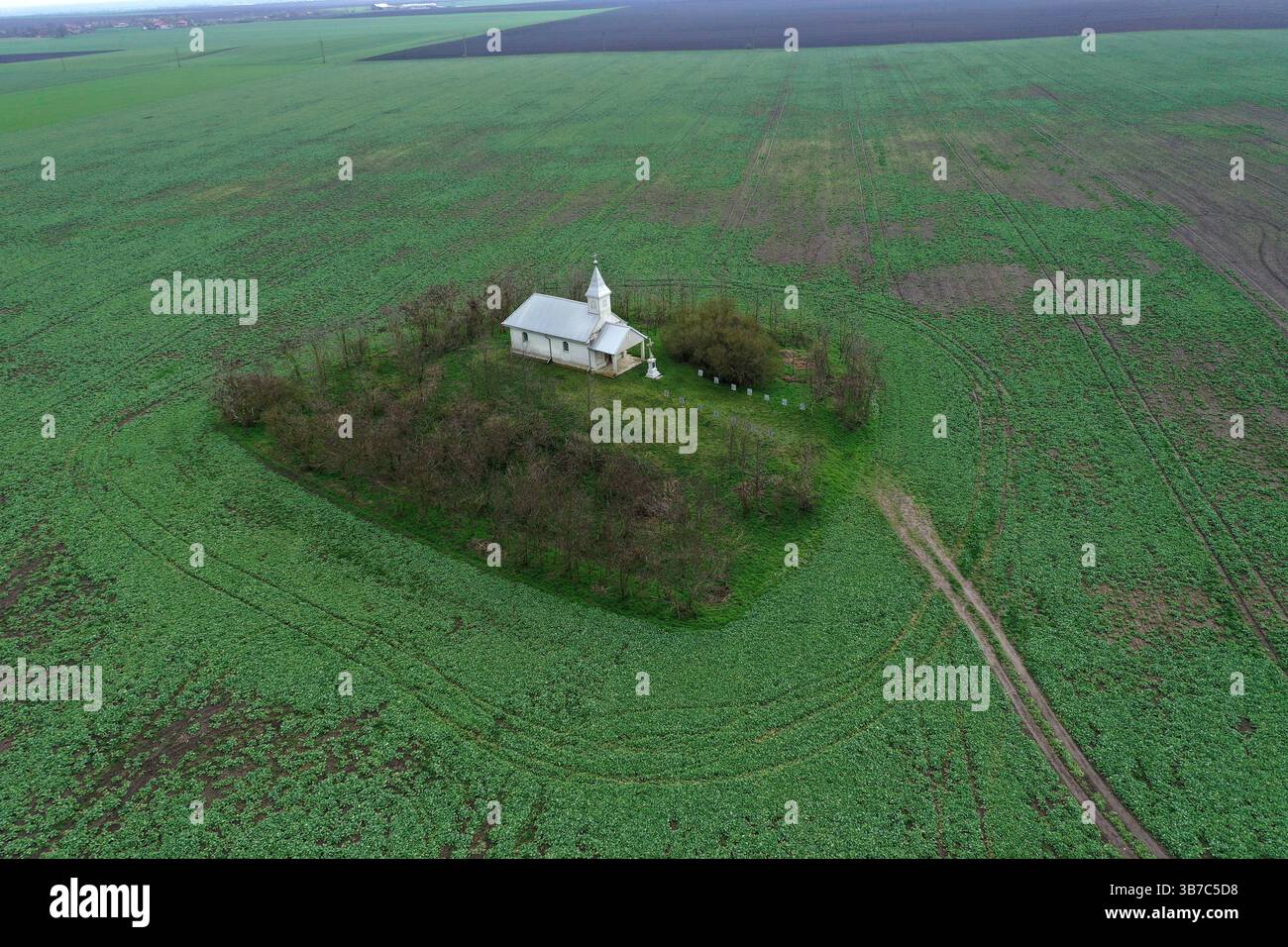 Aerial view of small white chapel in the middle of agricultural field ...
