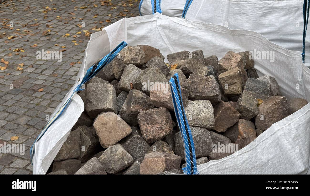 Large white construction bags filled with gray cobblestones on ...