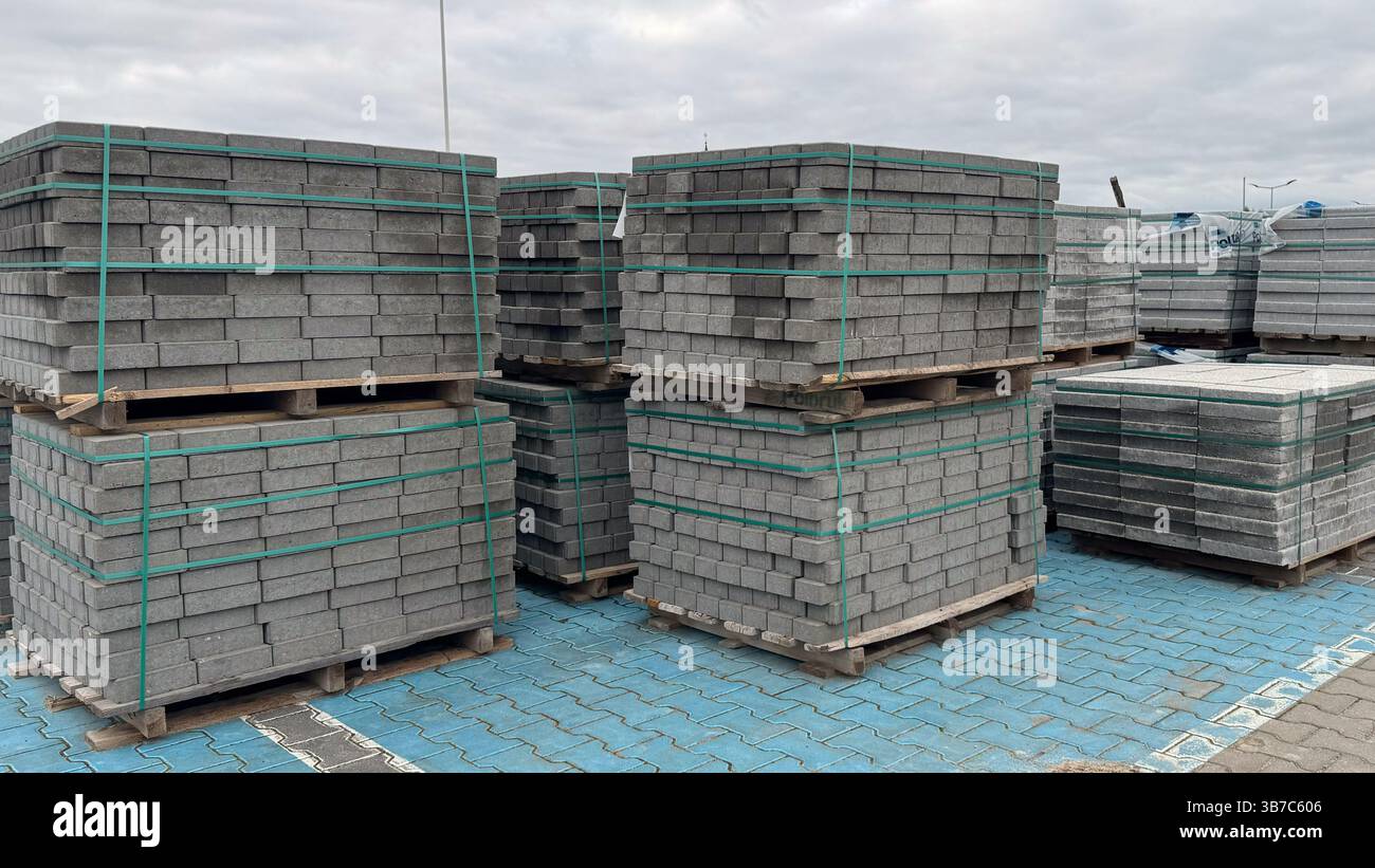 Stacks of gray concrete paving stones on wooden pallets in an outdoor ...