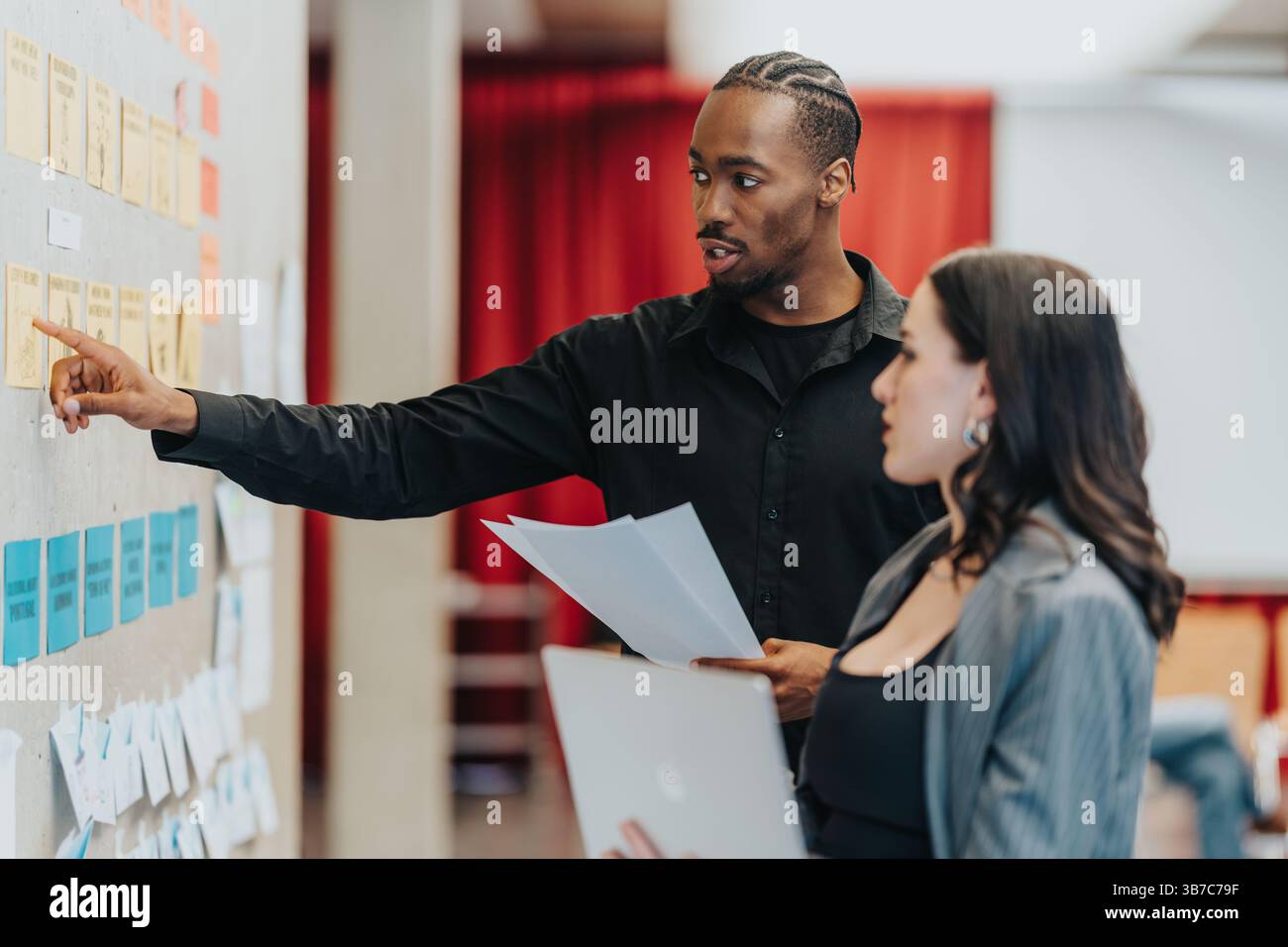 Two business people collaborating on a team project plan using a board ...