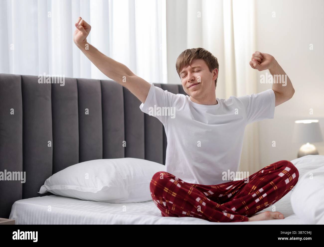 Young man stretching on bed indoors. Good morning Stock Photo - Alamy