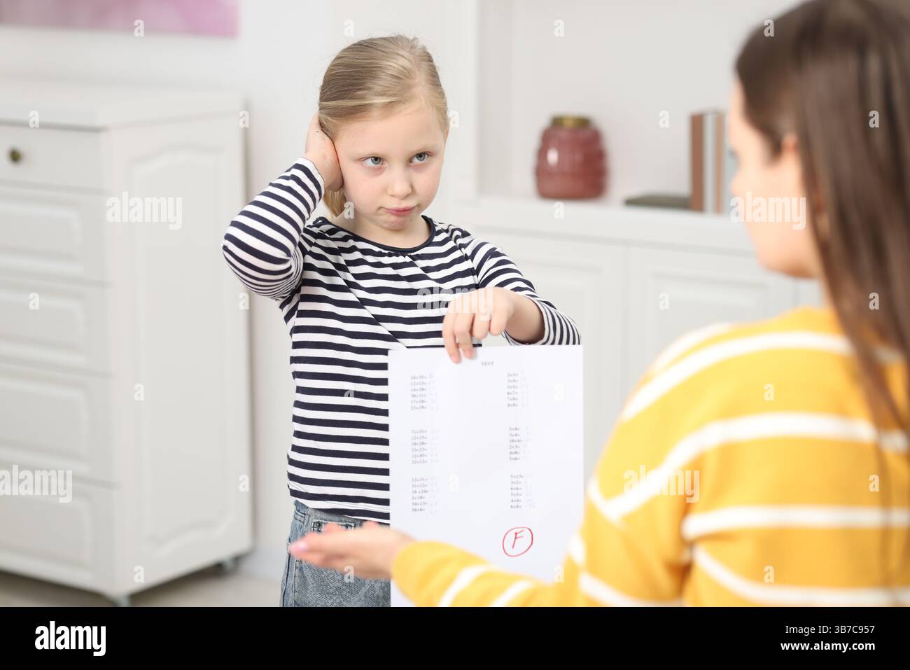 School grade. Sad girl showing answer sheet with bad mark to her mother ...