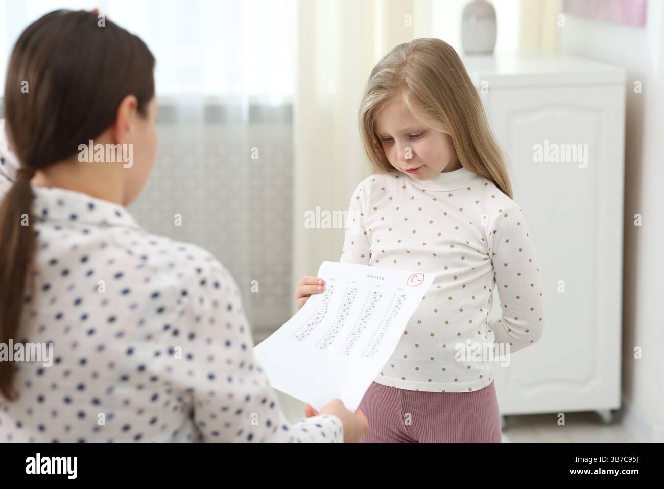 School grade. Sad girl showing answer sheet with bad mark to her mother ...