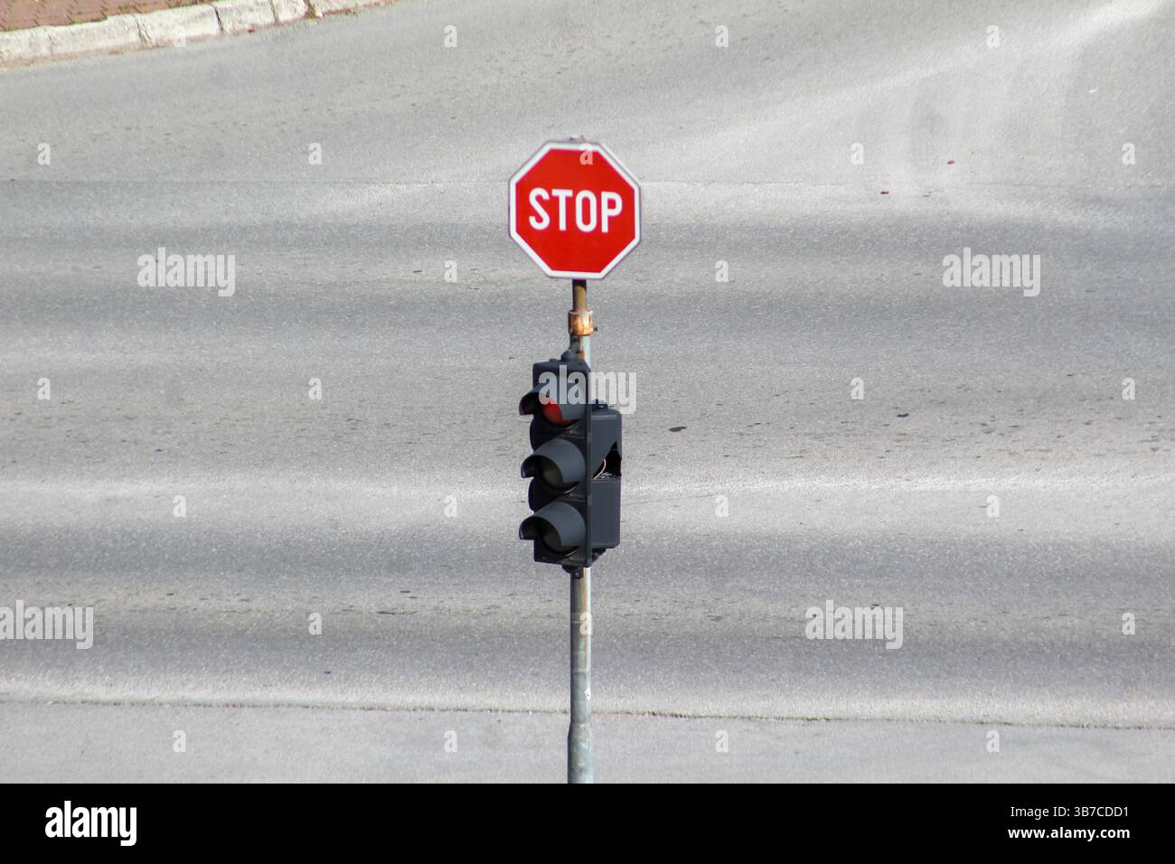 Close-up of a red stop sign above a traffic light on an empty asphalt ...