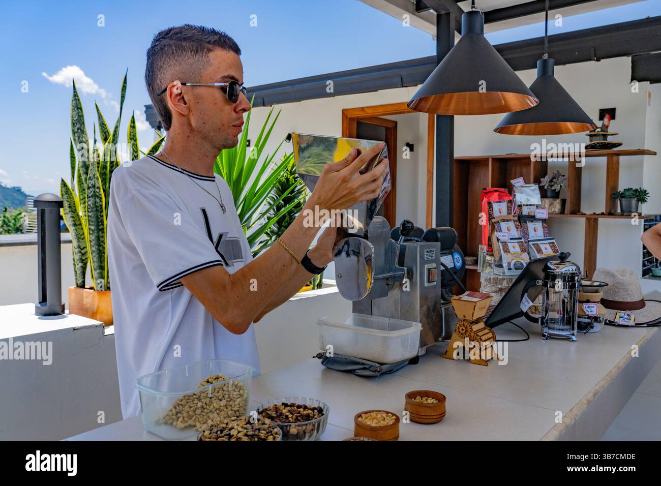 A man pours unhulled coffee beans into a huller machine during a tour ...