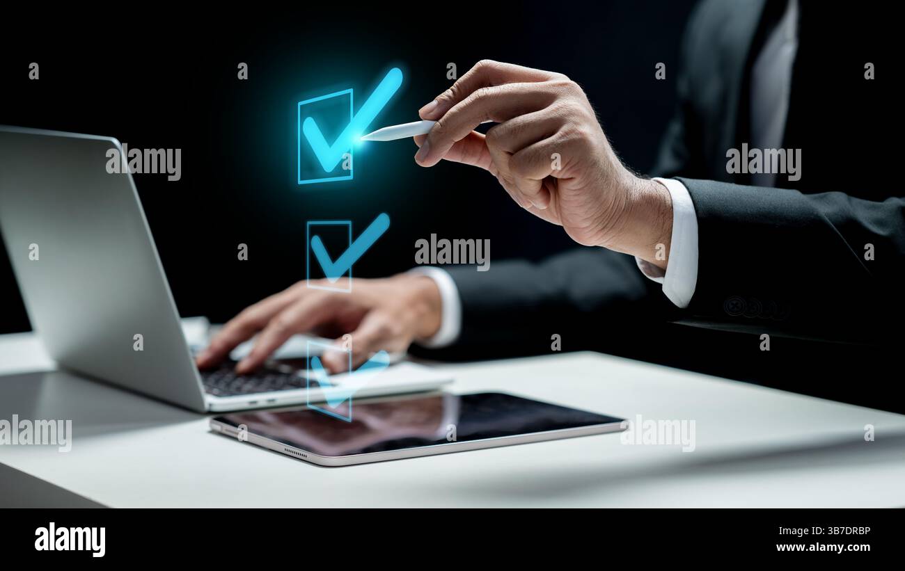 Businessman with laptop touching icon of check mark list on tablet ...
