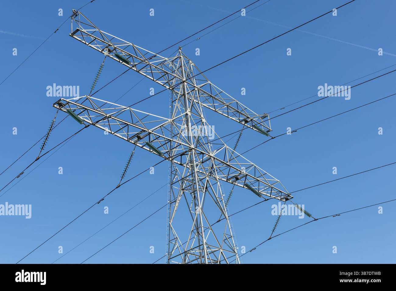 High-voltage power line and transmission tower against a clear blue sky ...