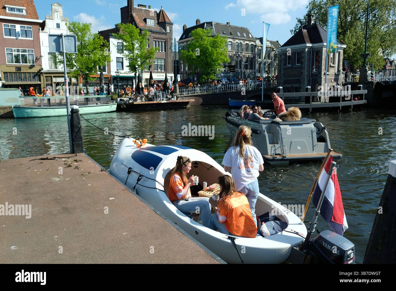 Women sit in a traditional Dutch wooden clog shaped boat docked at ...
