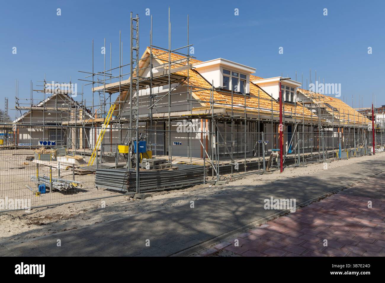 New row houses under construction with scaffolding and unfinished roofs ...