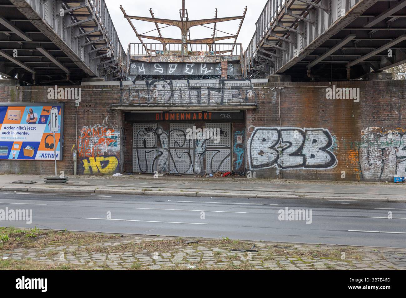 A brick underpass with graffiti is situated beneath a weathered metal ...