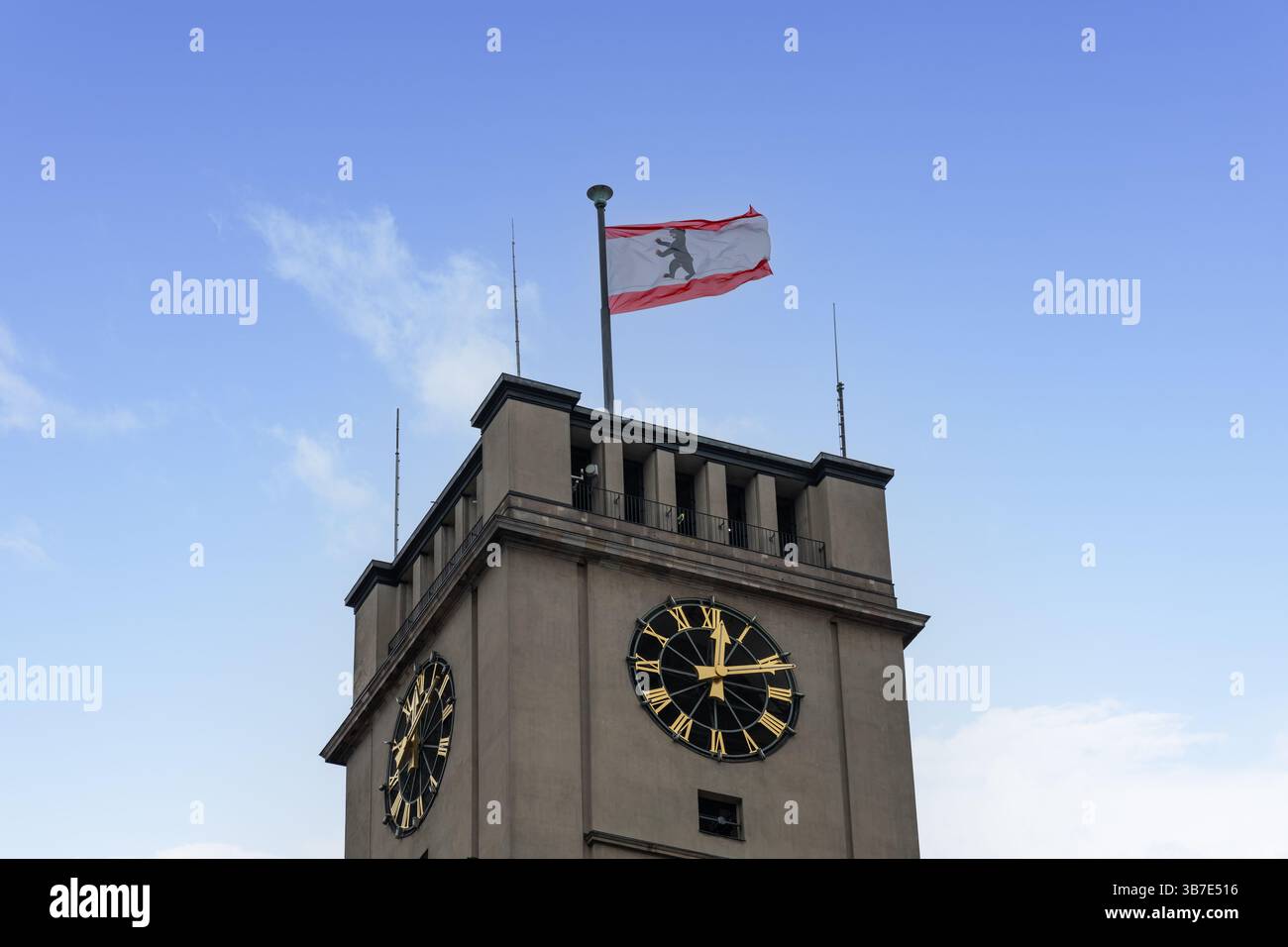 Clock tower with the Berlin city flag waving on top against a clear ...