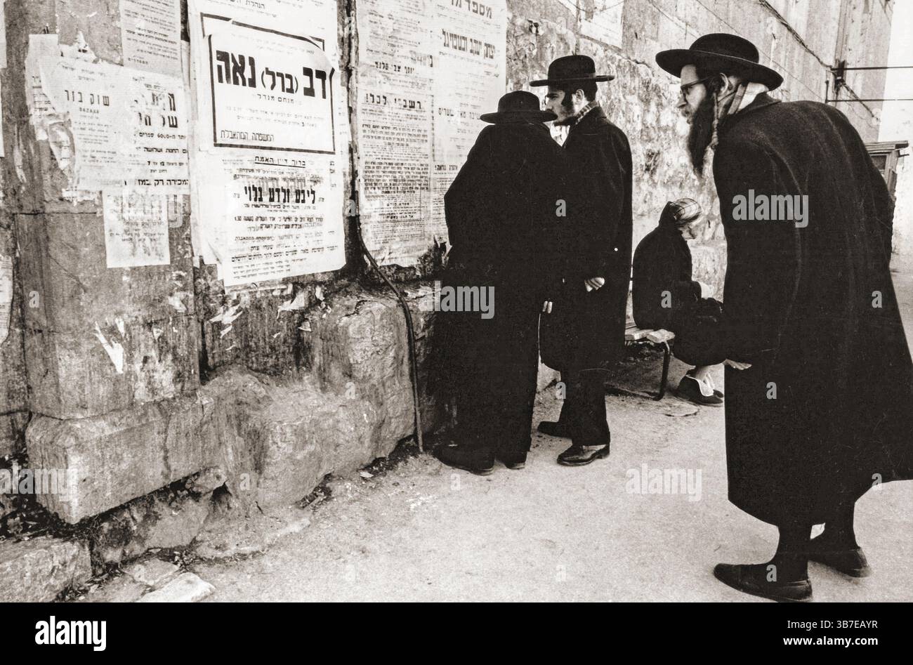 Ultra orthodox Jewish men read signs in Hebrew & Yiddish on a wall in ...