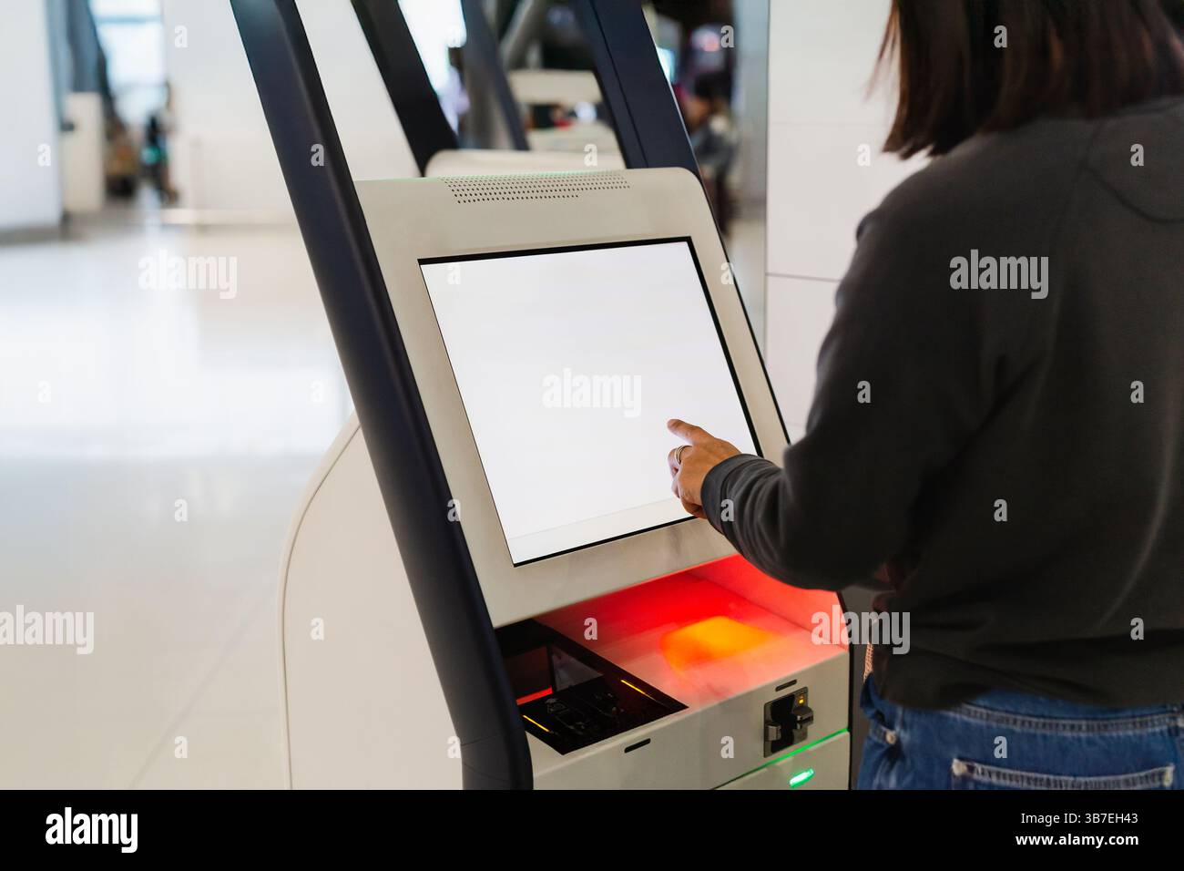 Woman at self service transfer area doing self check in at airport ...