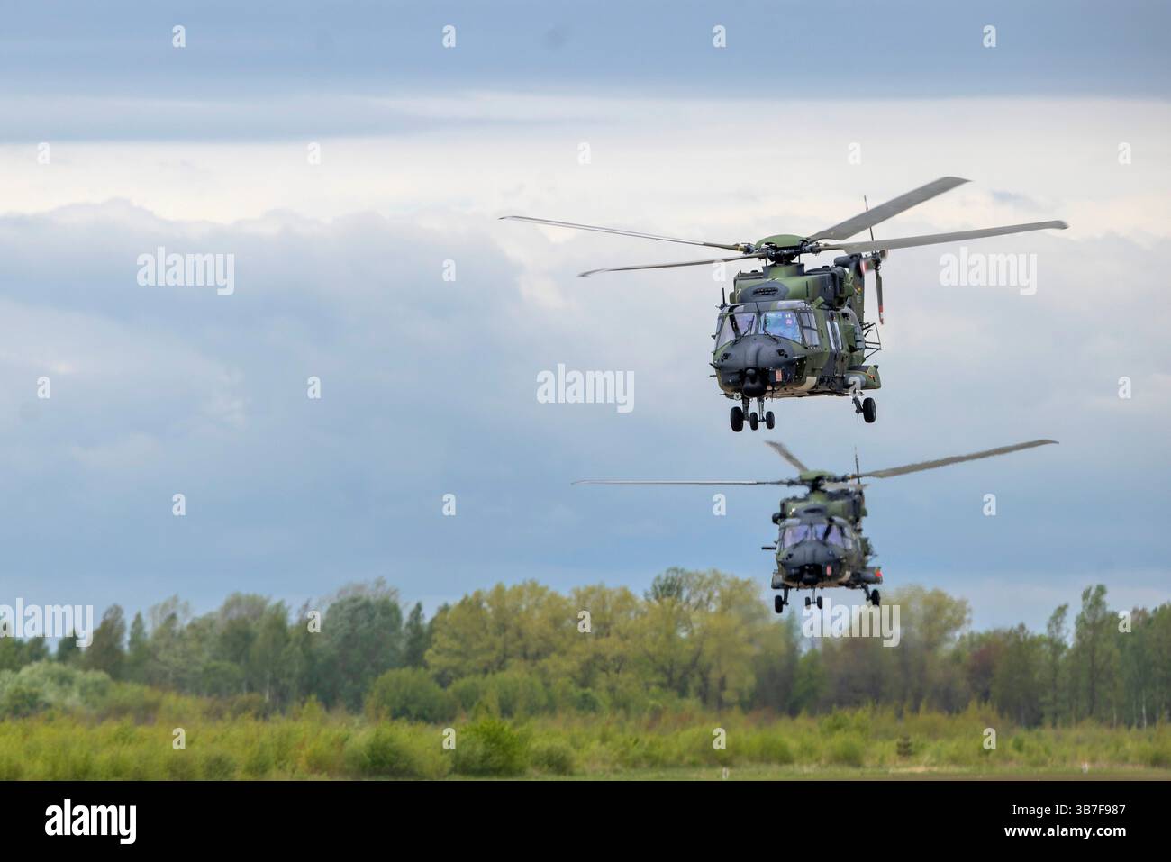 German Air Force NH90 transport helicopters fly over a field during a ...
