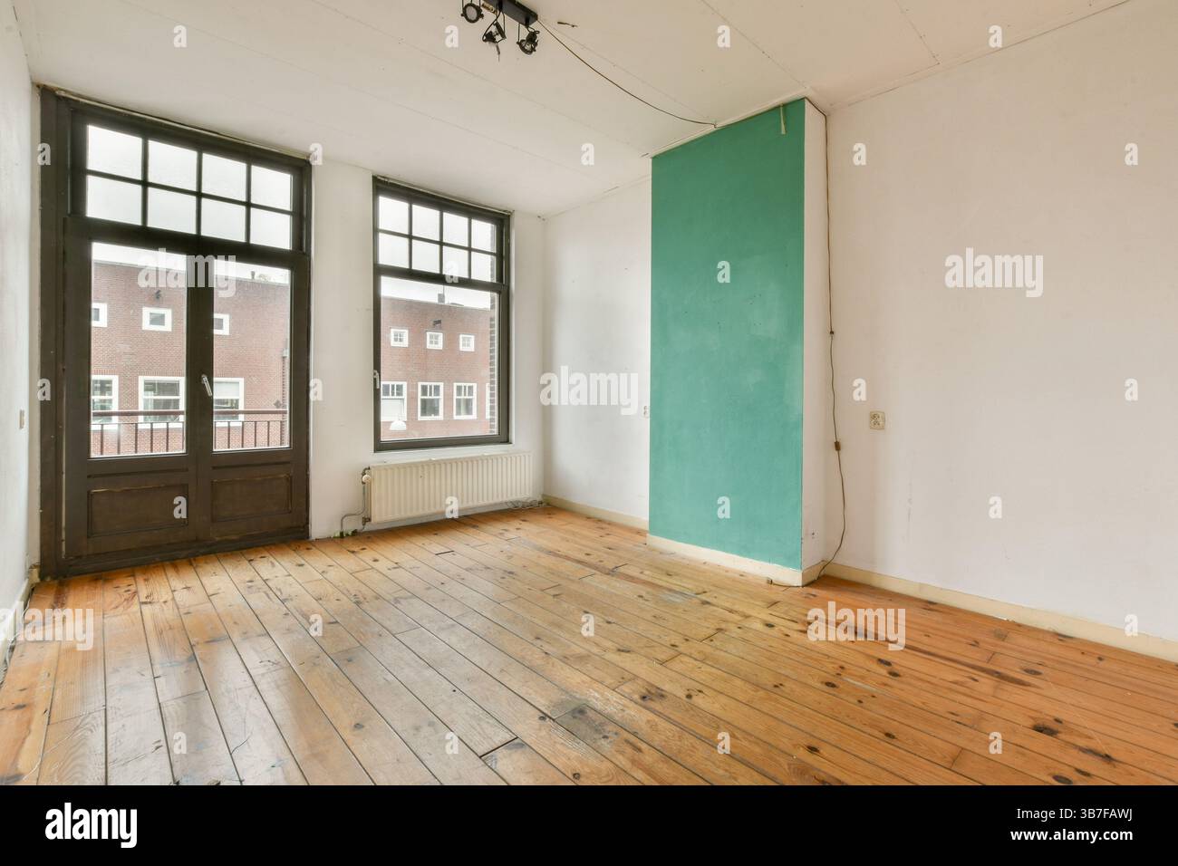 An empty room featuring wooden flooring and large windows that allow ...