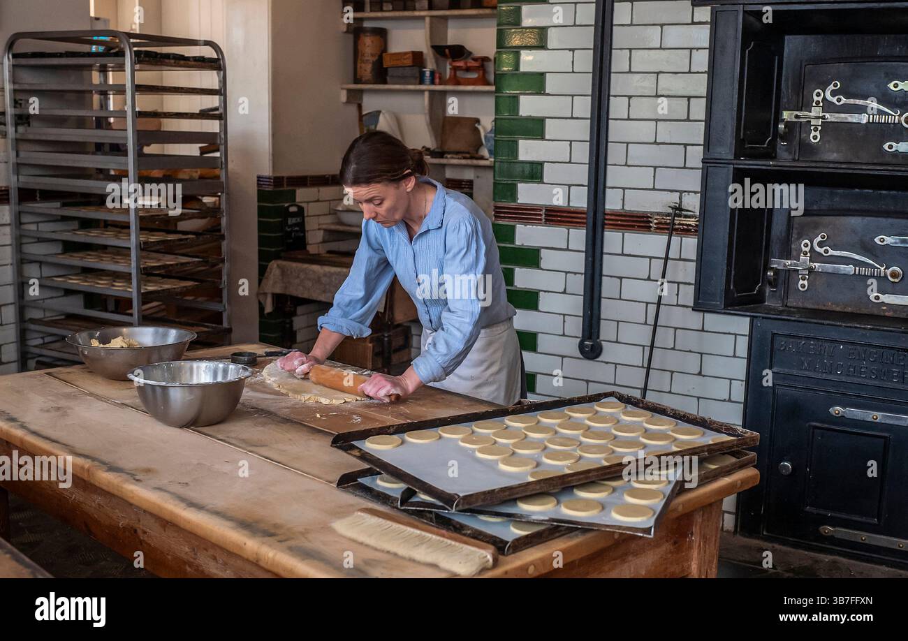 A woman in period costume bakes biscuits in a bakery in the 1900s ...