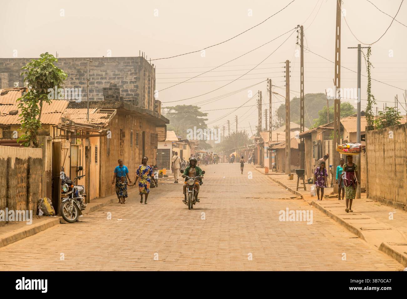 Street scene in Ouidah, Benin. Locals walking and working amidst ...