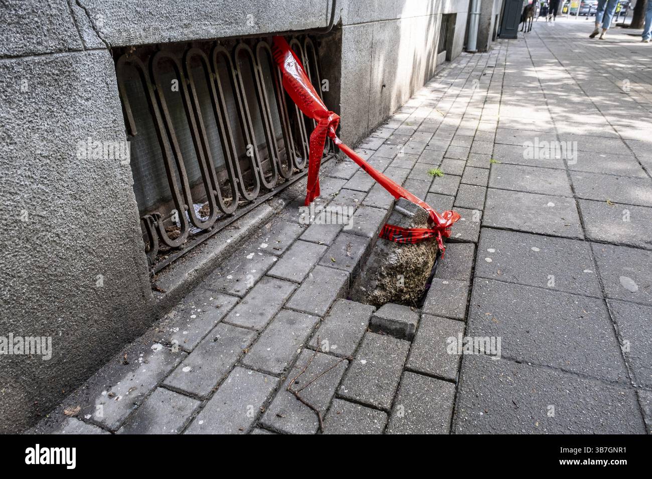 Loose paving slab with barrier tape as a temporary warning on the ...