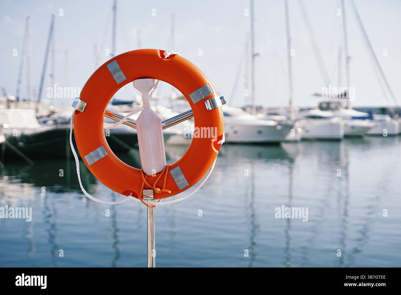 Red lifebuoy on a metal stand with white plastic fastener by the sea ...