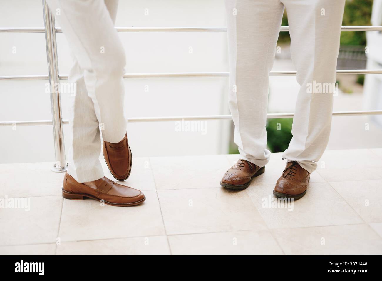 The legs of two men standing on the balcony, close-up. The groom and ...