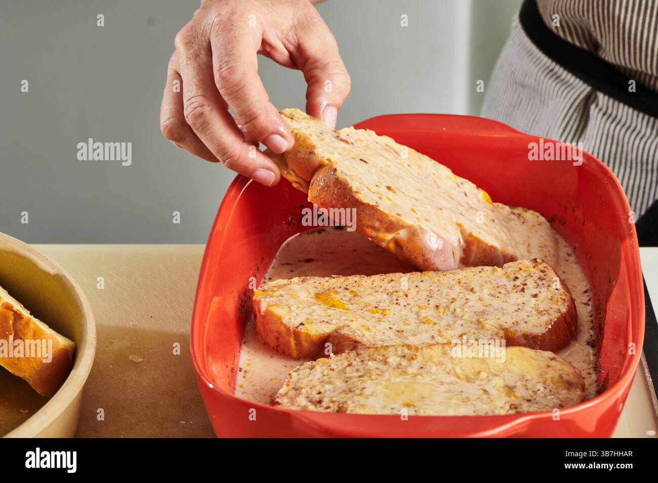 Challah slices are dipped into an egg custard to make French toast in ...