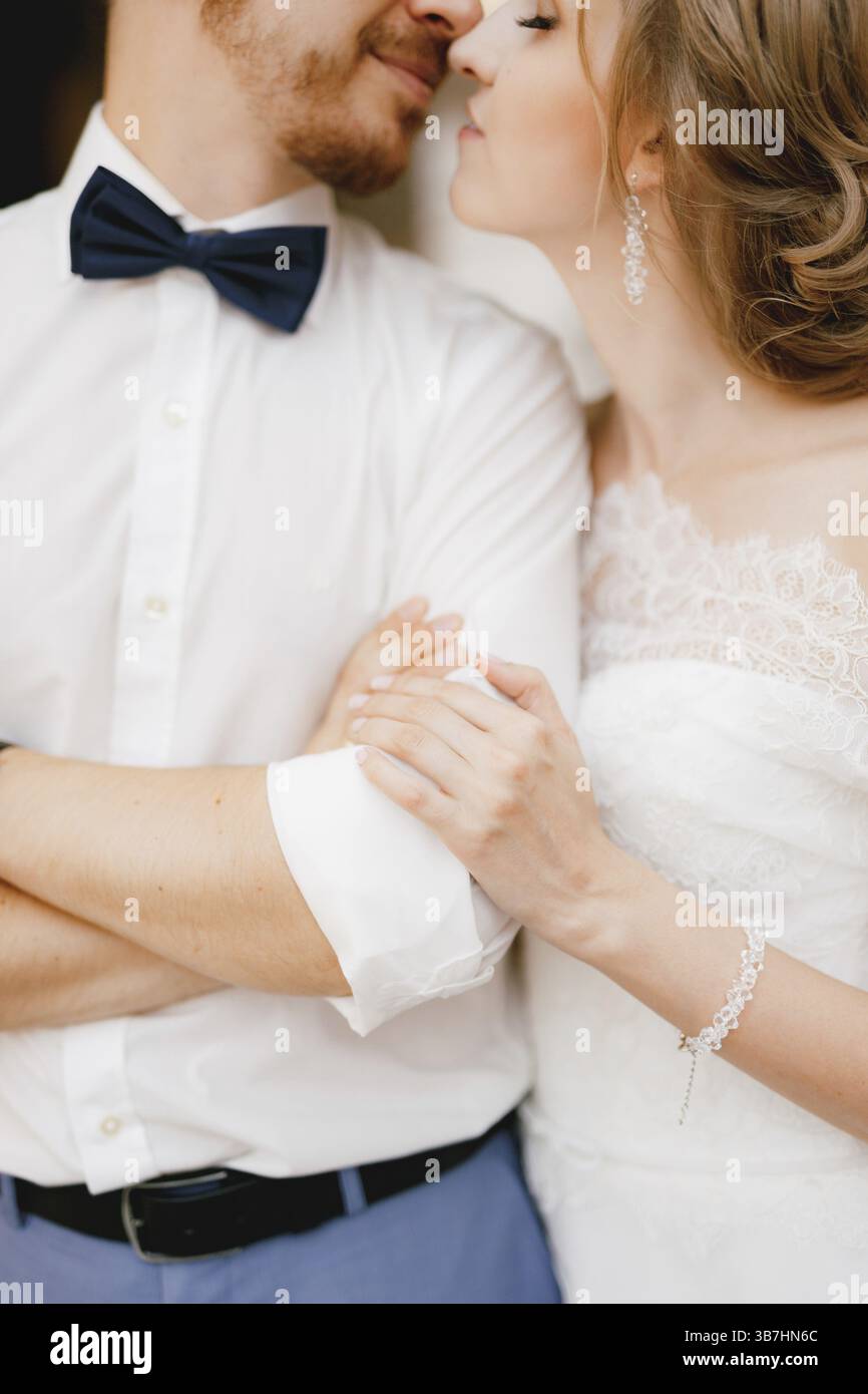 The groom folded his arms over his chest, the bride gently hugs him by the elbow and is about to ...
