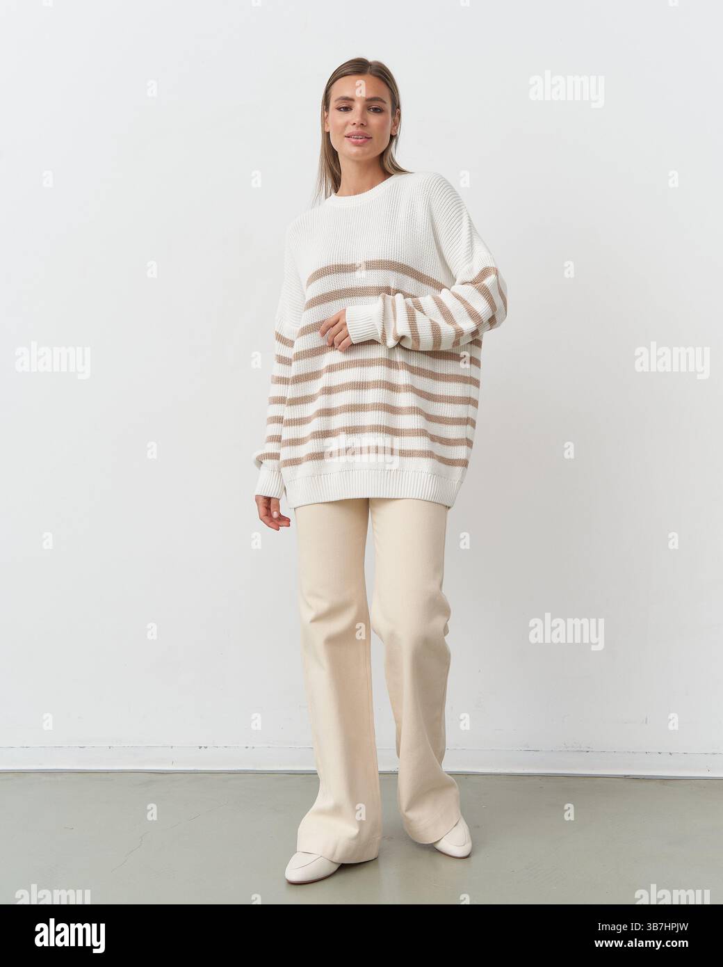 Elegant fashion model poses effortlessly in a chic striped sweater in a ...