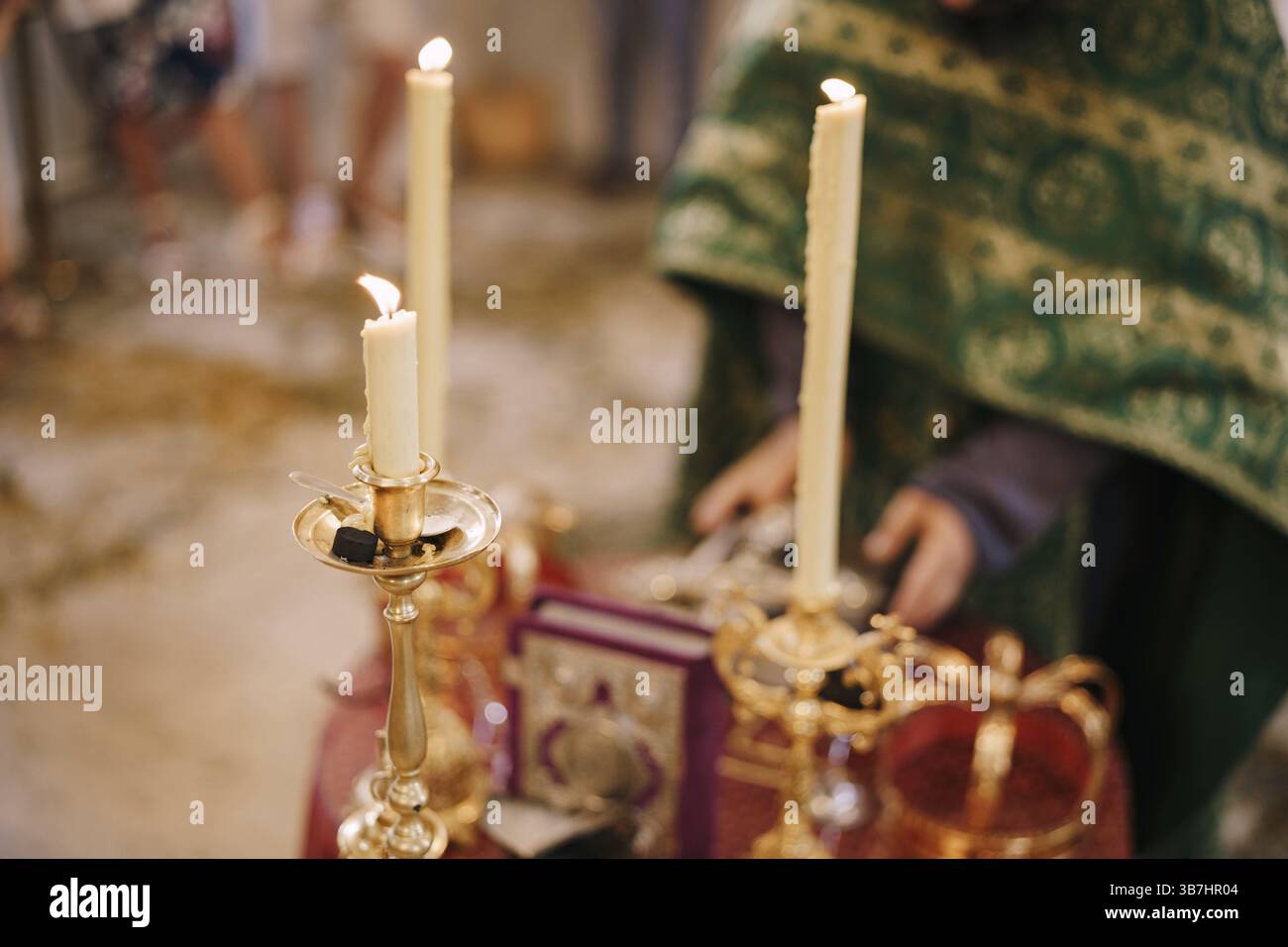 Candles are burning on candlesticks in front of the priest in the ...
