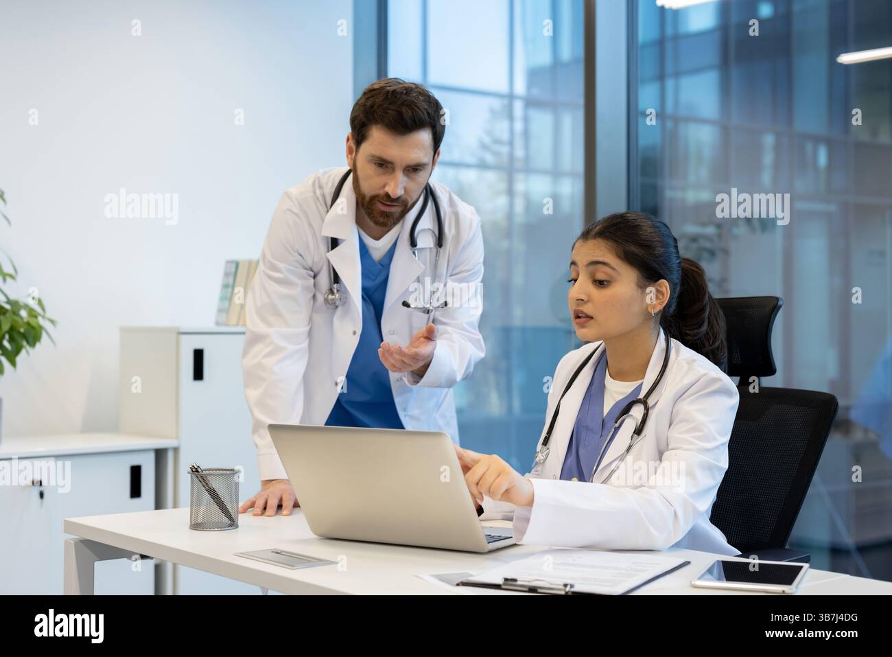 Two doctors collaborate in a modern office setting, focusing on a ...