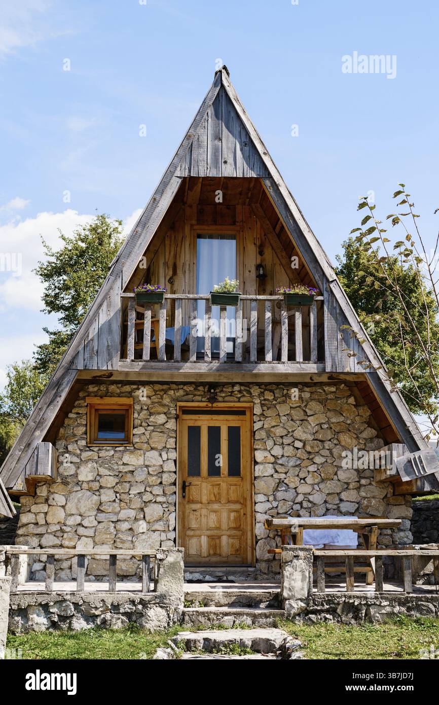 Two-storey triangular house with a terrace, a table and a bench at the ...